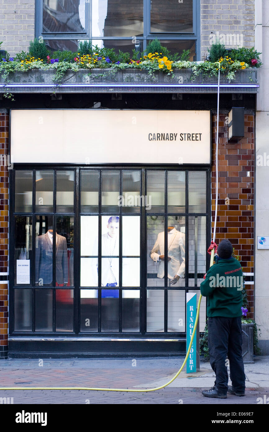 Workman watering the high window box flowers on Carnaby Street London ...