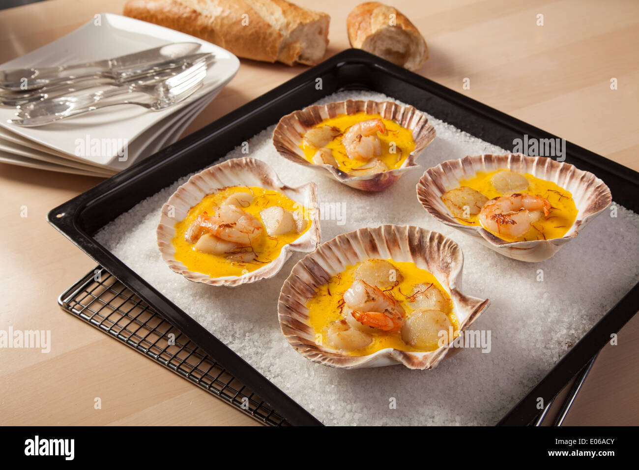 shrimps and scallops in saffron sauce baked in empty shells on a bed of ...