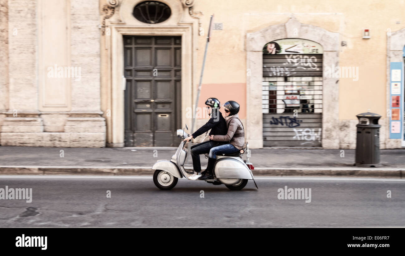 Young Man and young Woman driving on a Scooter through the inner City ...