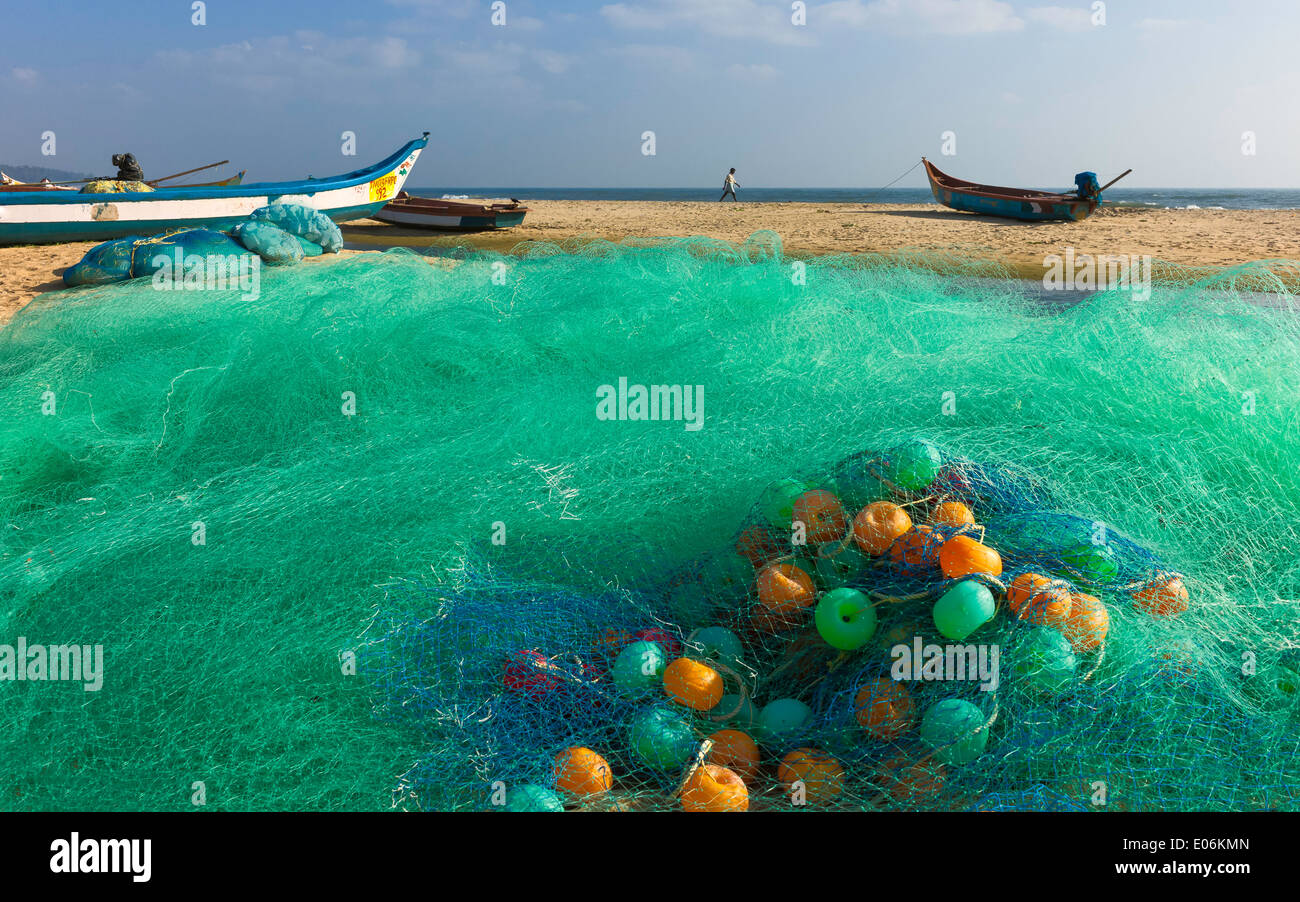 A large fishing net as a fisherman walks across the sandy beach on ...