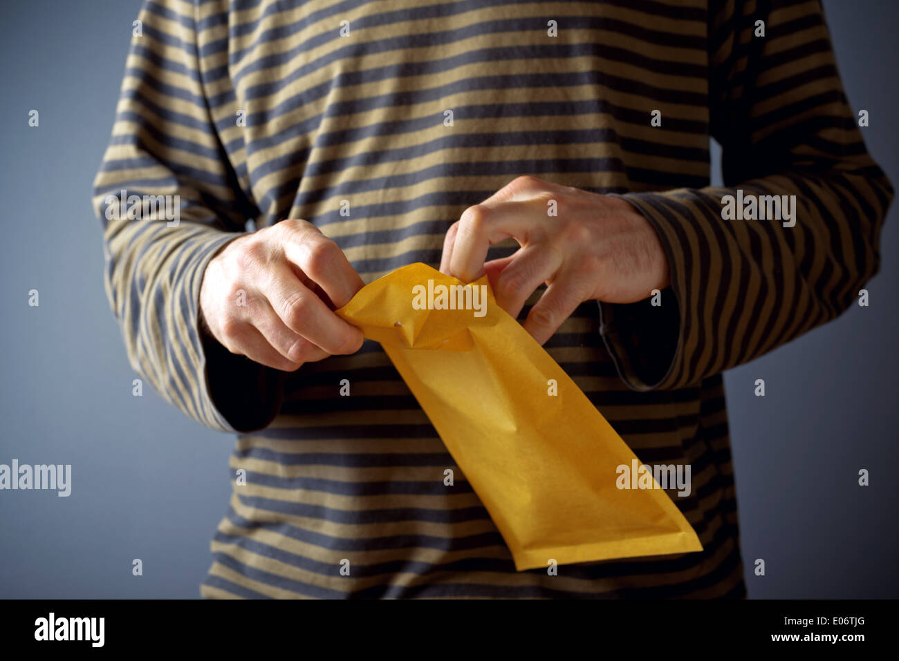 Casual man is opening yellow document postal envelope Stock Photo - Alamy