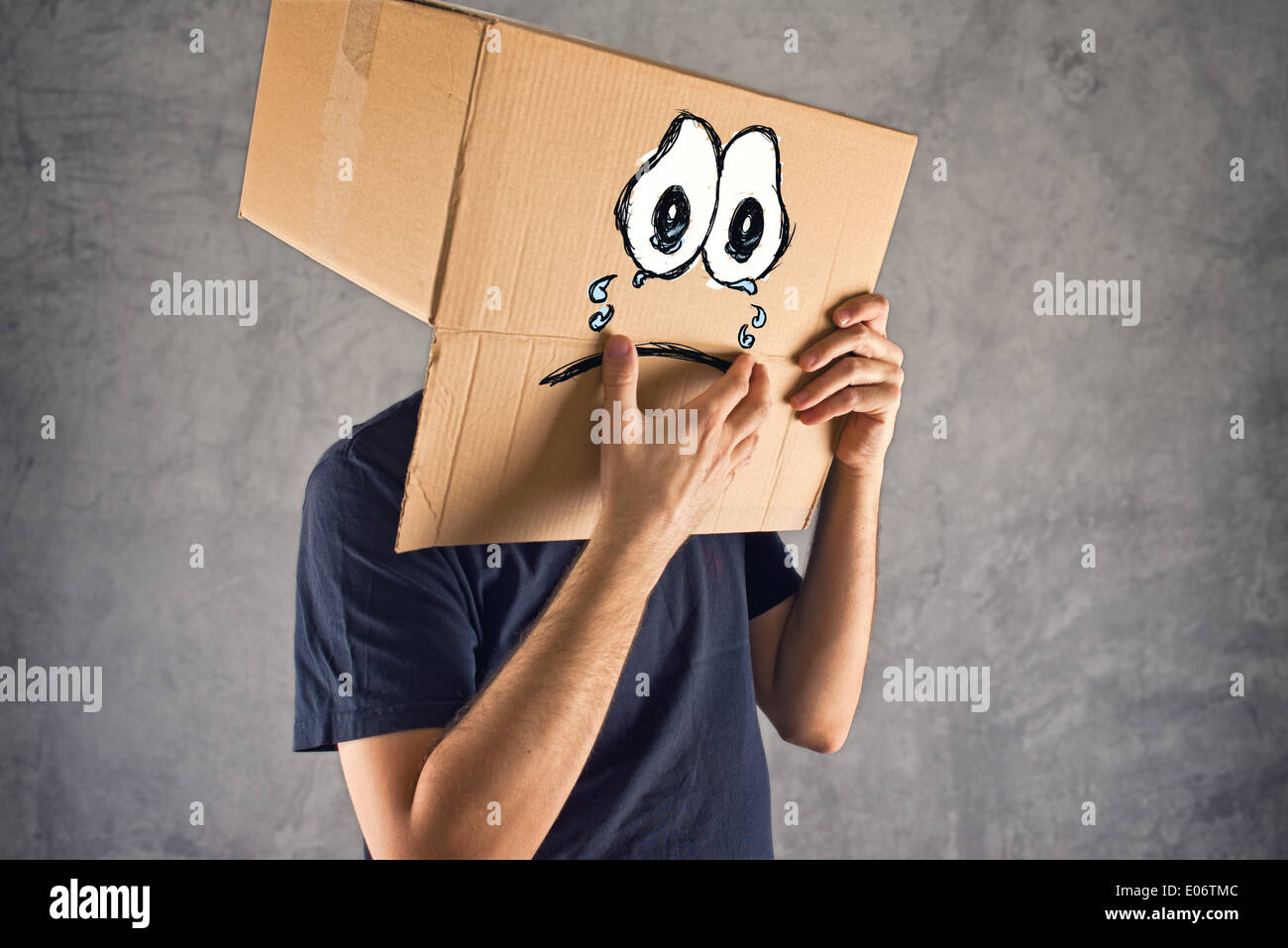 Man with cardboard box on his head and sad crying face expression ...