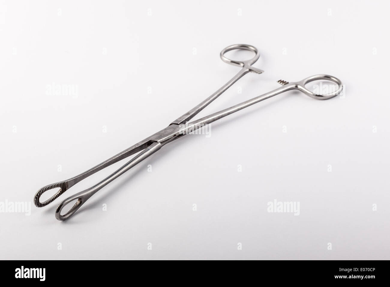 a pair of stainless steel surgical forceps over a white background ...