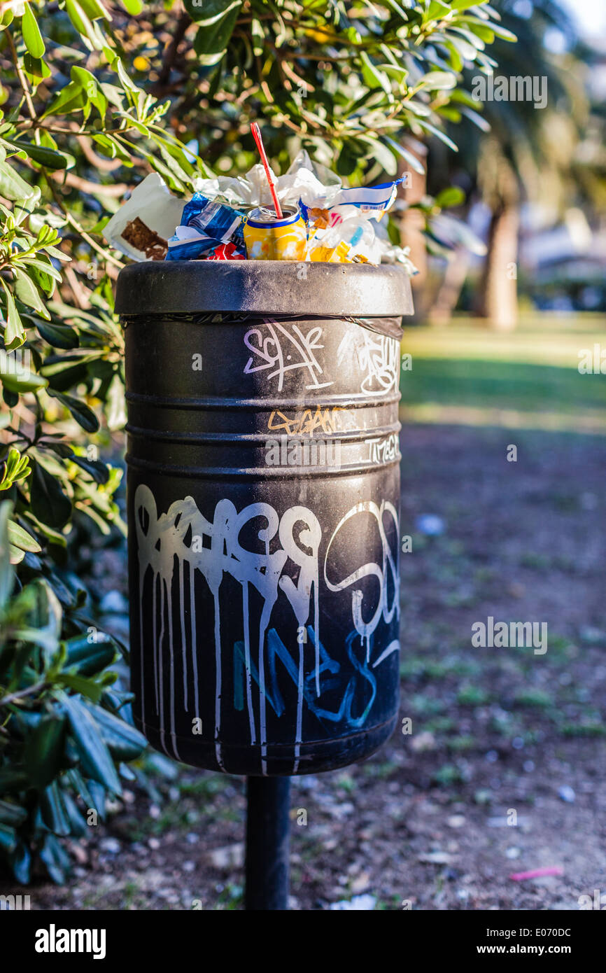an overfilled and vandalized trash can in a park Stock Photo - Alamy