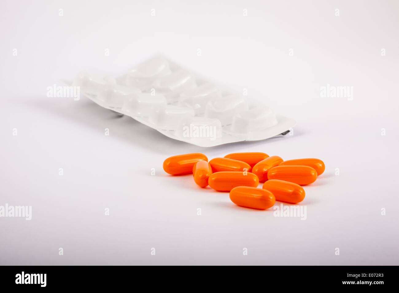some orange pills and an empty white blister on a white table Stock ...