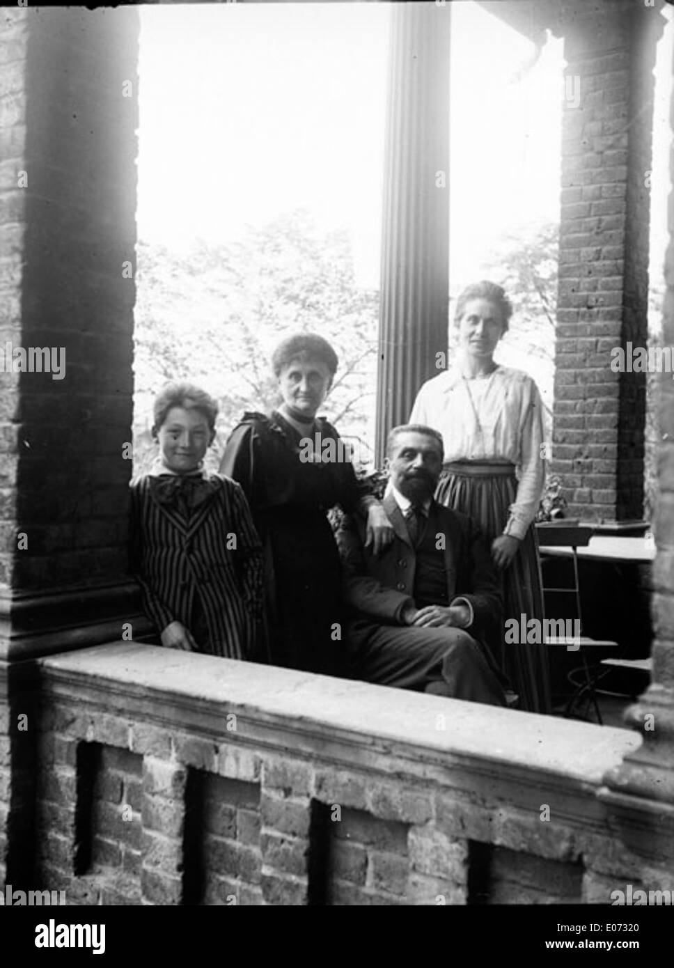 This family photograph captures individuals posed on the front steps of ...