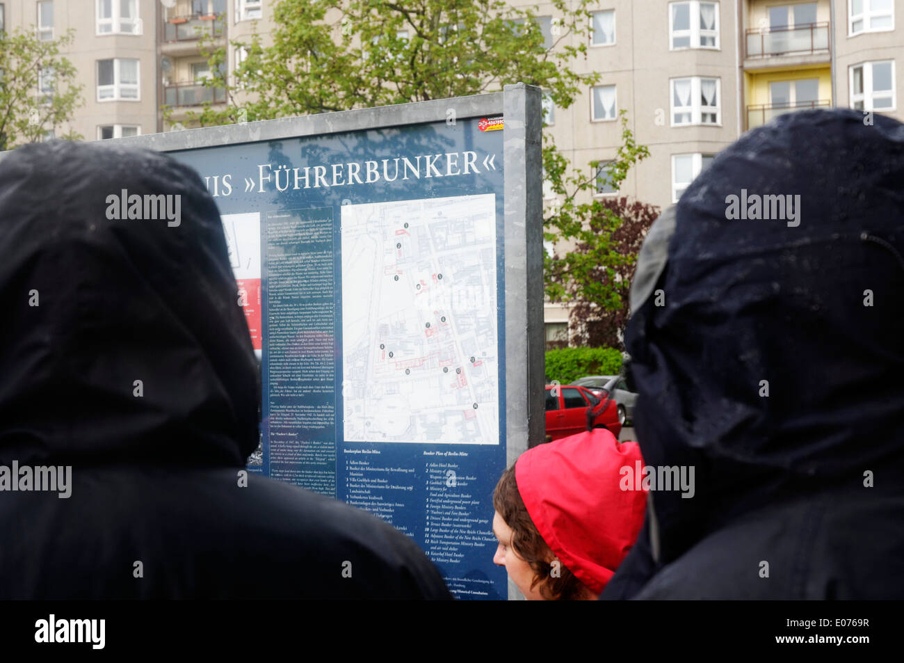Tourists on a walking tour of Berlin gathered round the sign that shows ...