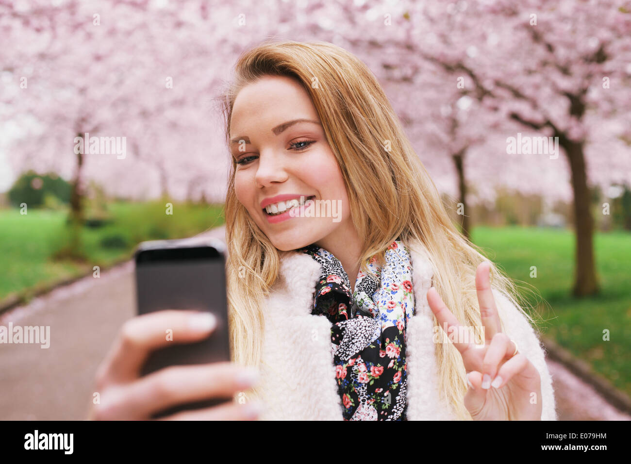 Pretty young female model gesturing peace sign while taking her picture ...