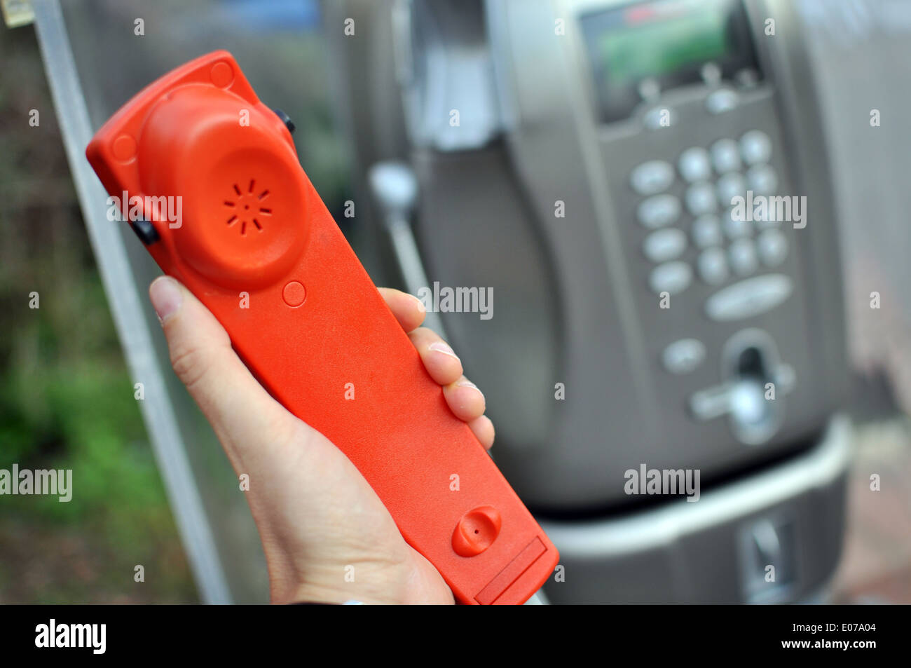 Hand holding a red handset of a public telephone Stock Photo - Alamy