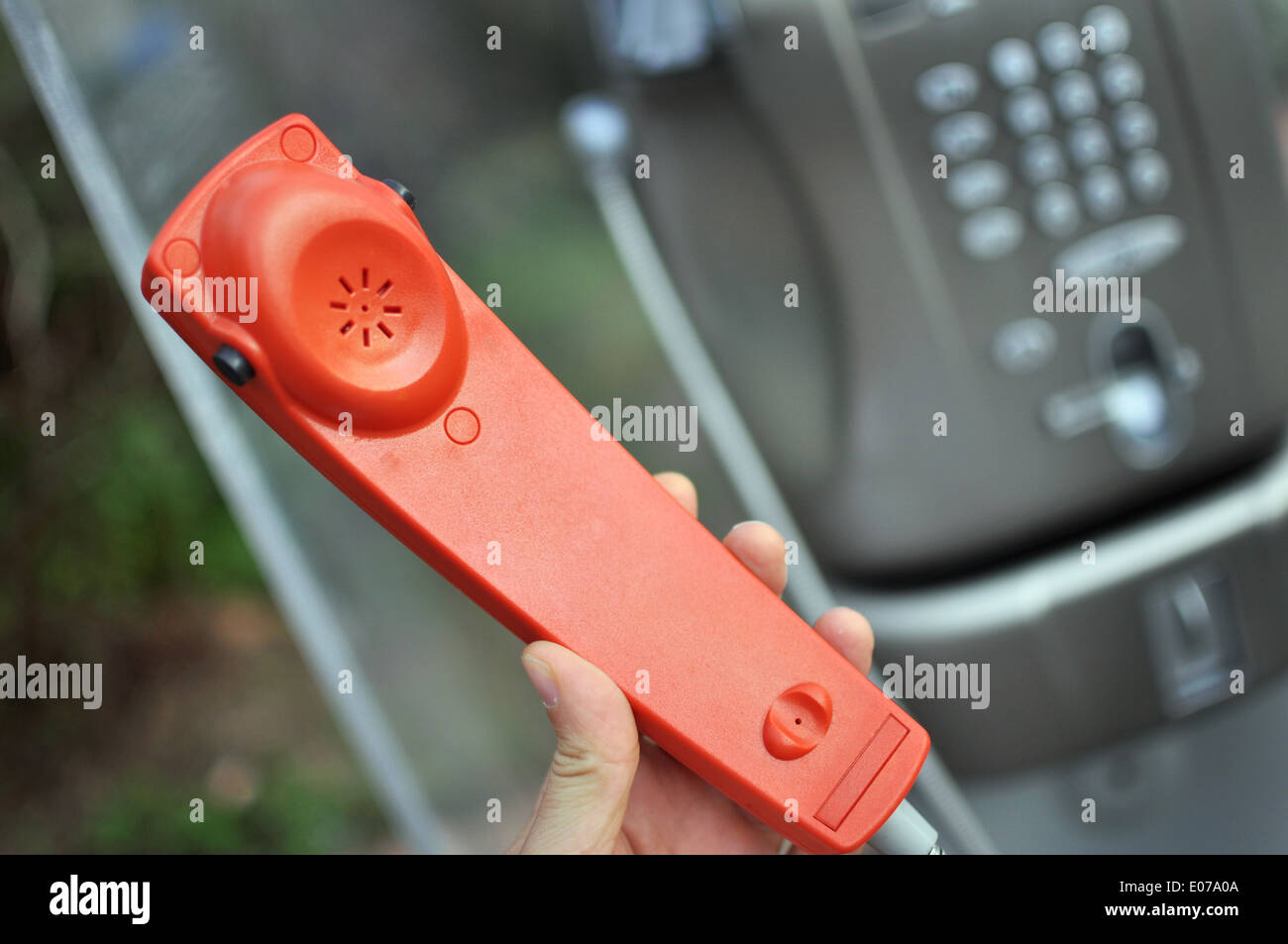 Hand holding a red handset of a public telephone Stock Photo - Alamy