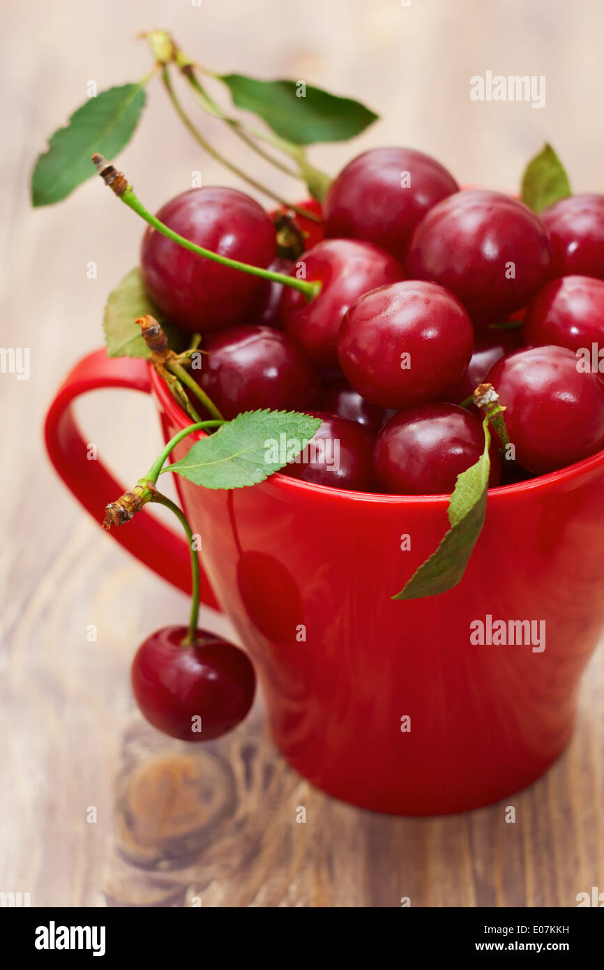 Sweet cherries in red cup on table close-up Stock Photo - Alamy