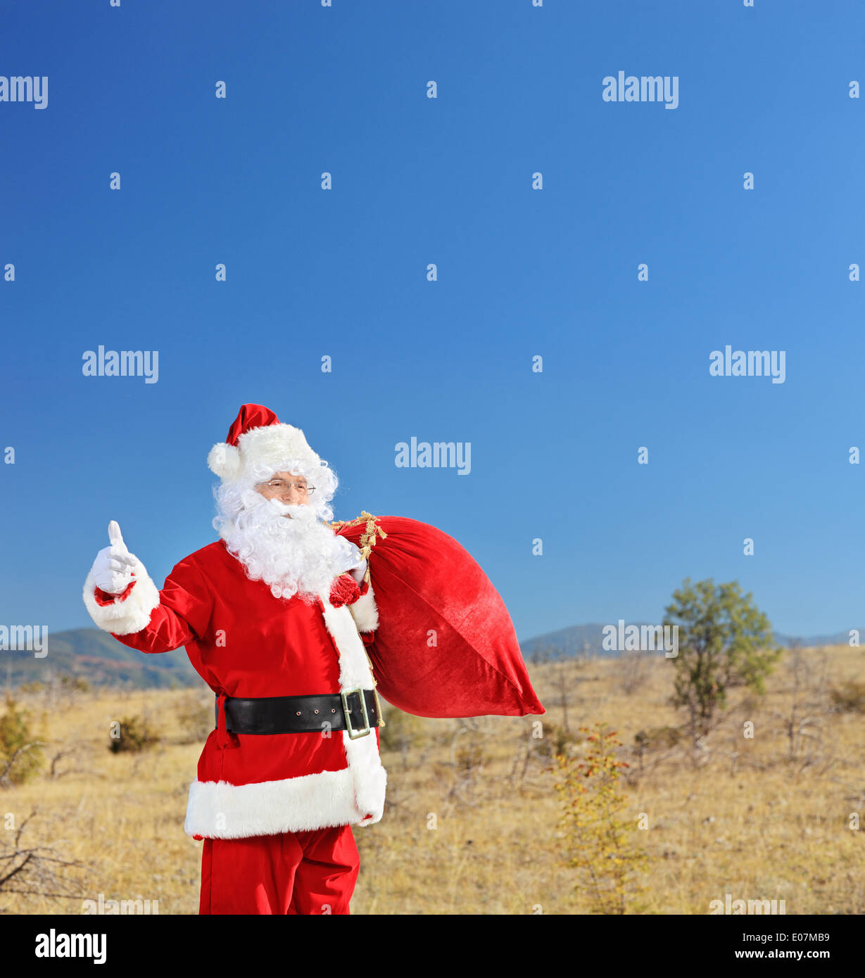 Santa holding a bag of presents and hitchhiking outdoors shot with tilt ...