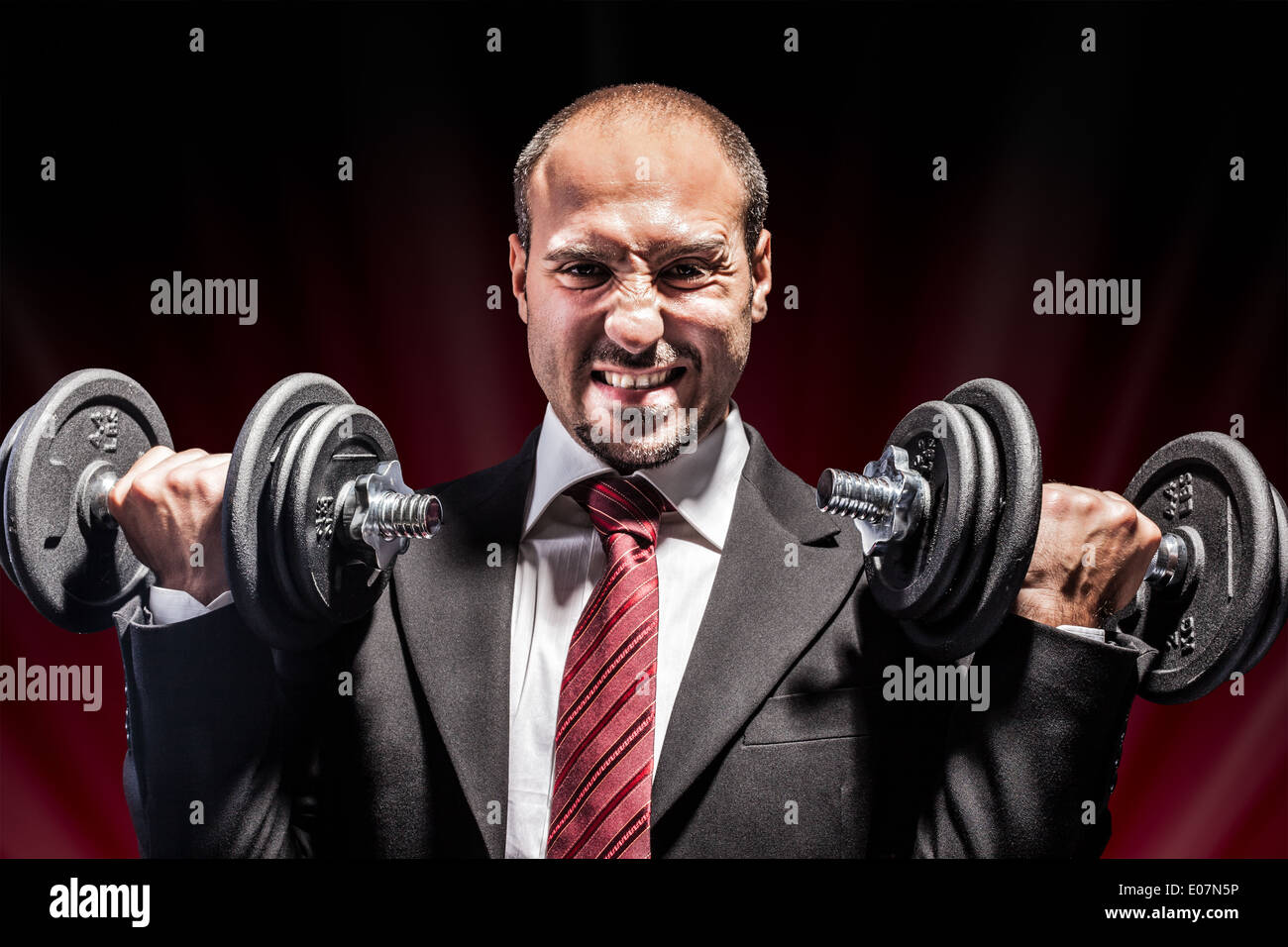 a serious businessman wearing a suit and lifting two heavy weight Stock ...