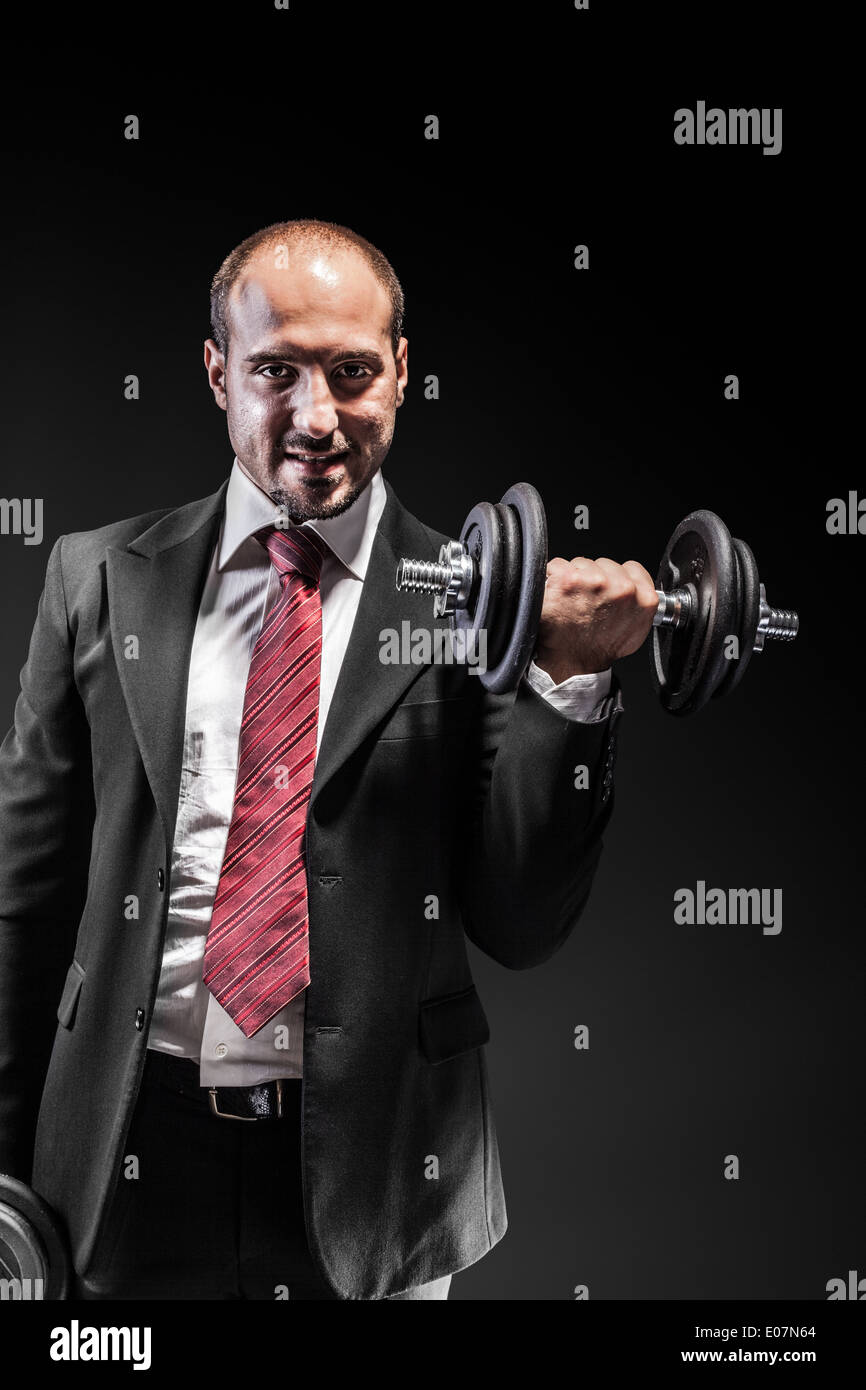 a serious businessman wearing a suit and lifting two heavy weight Stock ...