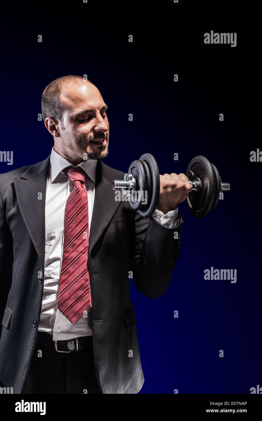 a serious businessman wearing a suit and lifting two heavy weight Stock ...