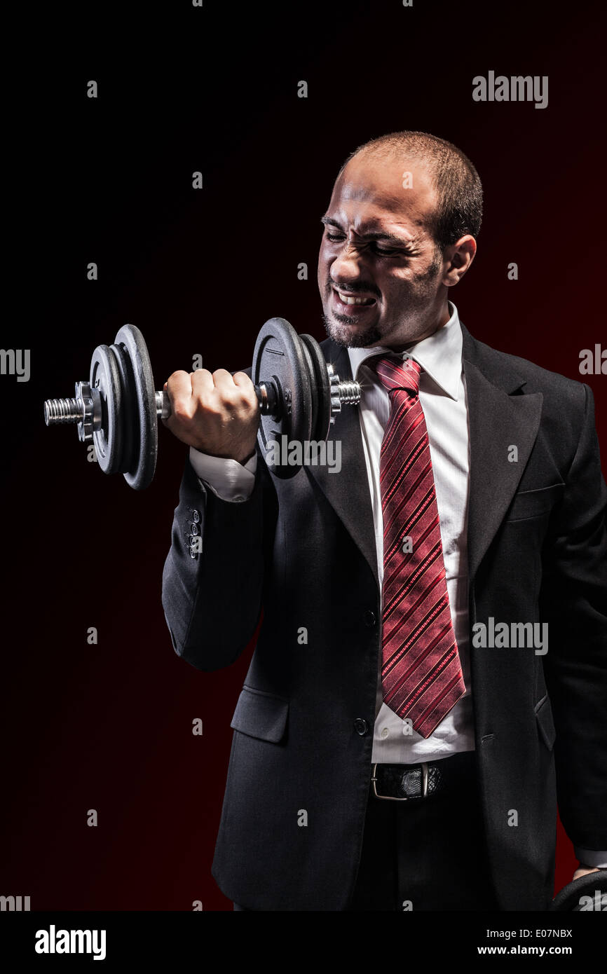 a serious businessman wearing a suit and lifting two heavy weight Stock ...
