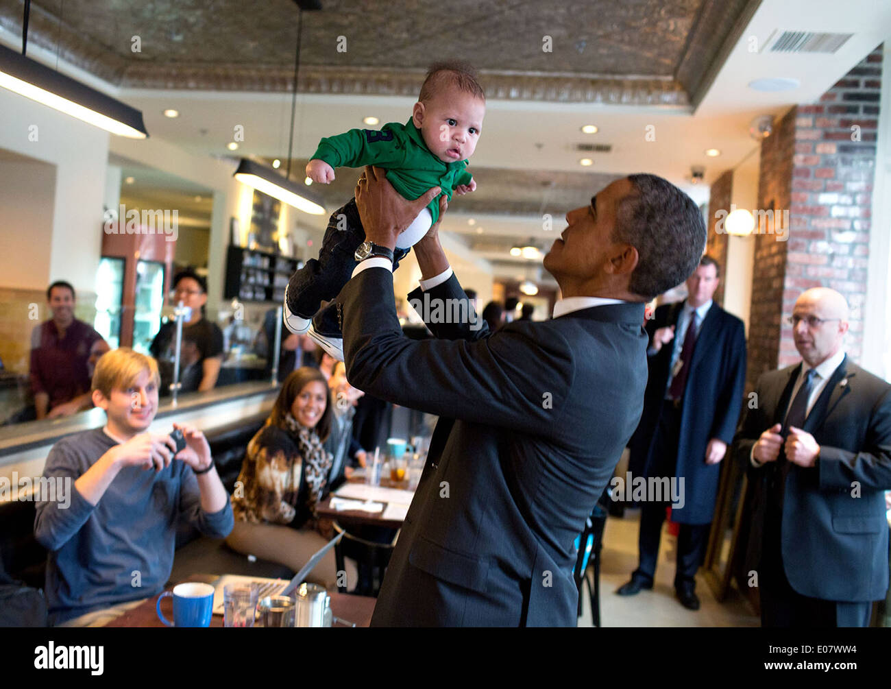 US President Barack Obama lifts a baby while greeting patrons prior to ...