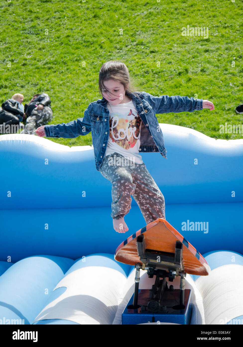 A young girl rides a surf board simulator Stock Photo - Alamy