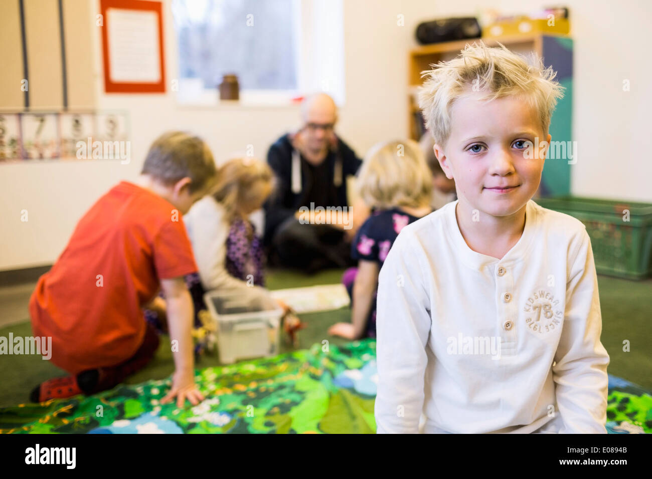 Portrait of boy with teacher and classmates in background at ...