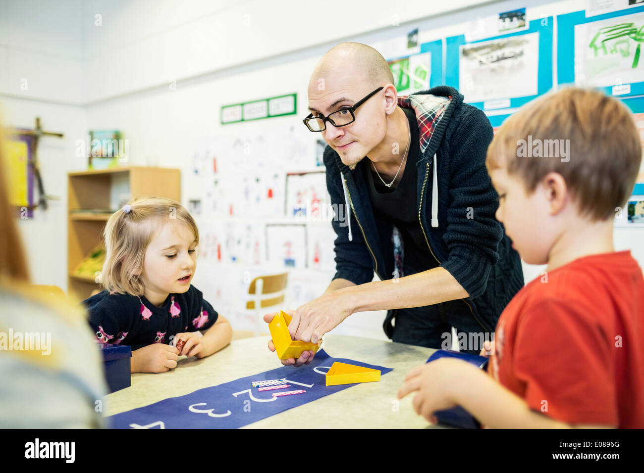 Male teacher assisting students in art class at kindergarten Stock ...