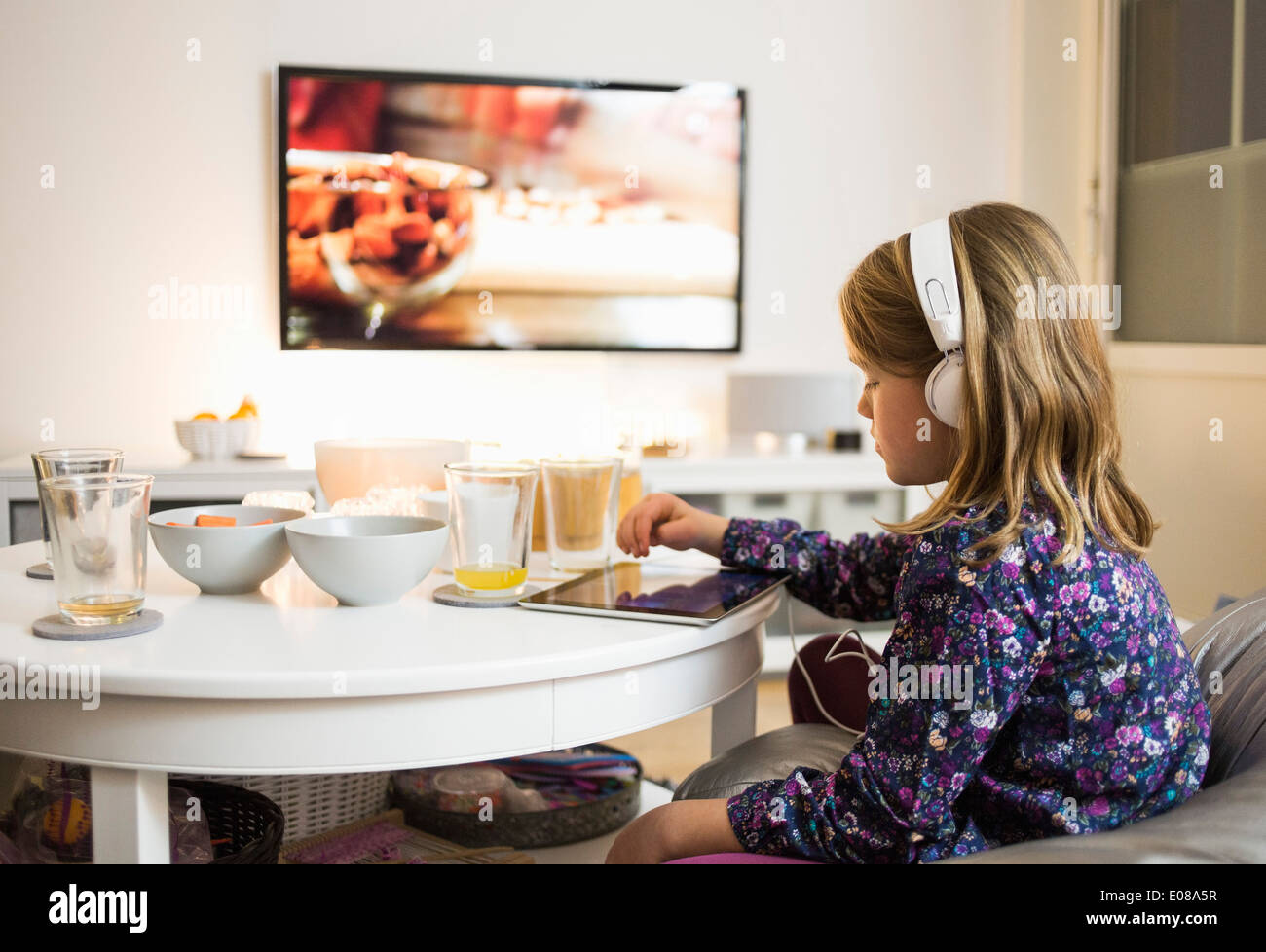 Side view of girl using digital tablet at coffee table in living room ...