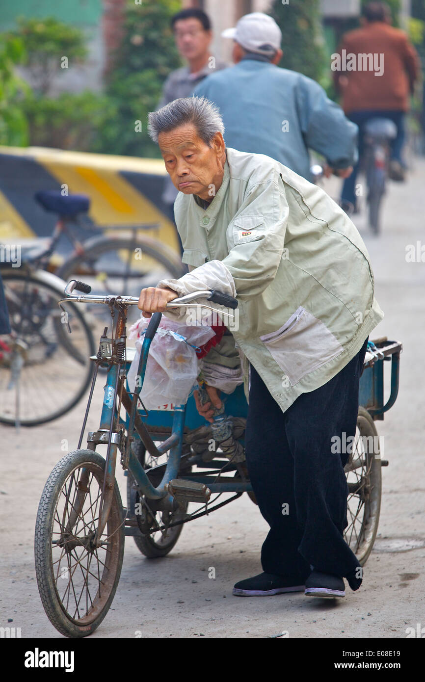 Elderly Chinese Man pushes his cycle rickshaw through the backstreets ...