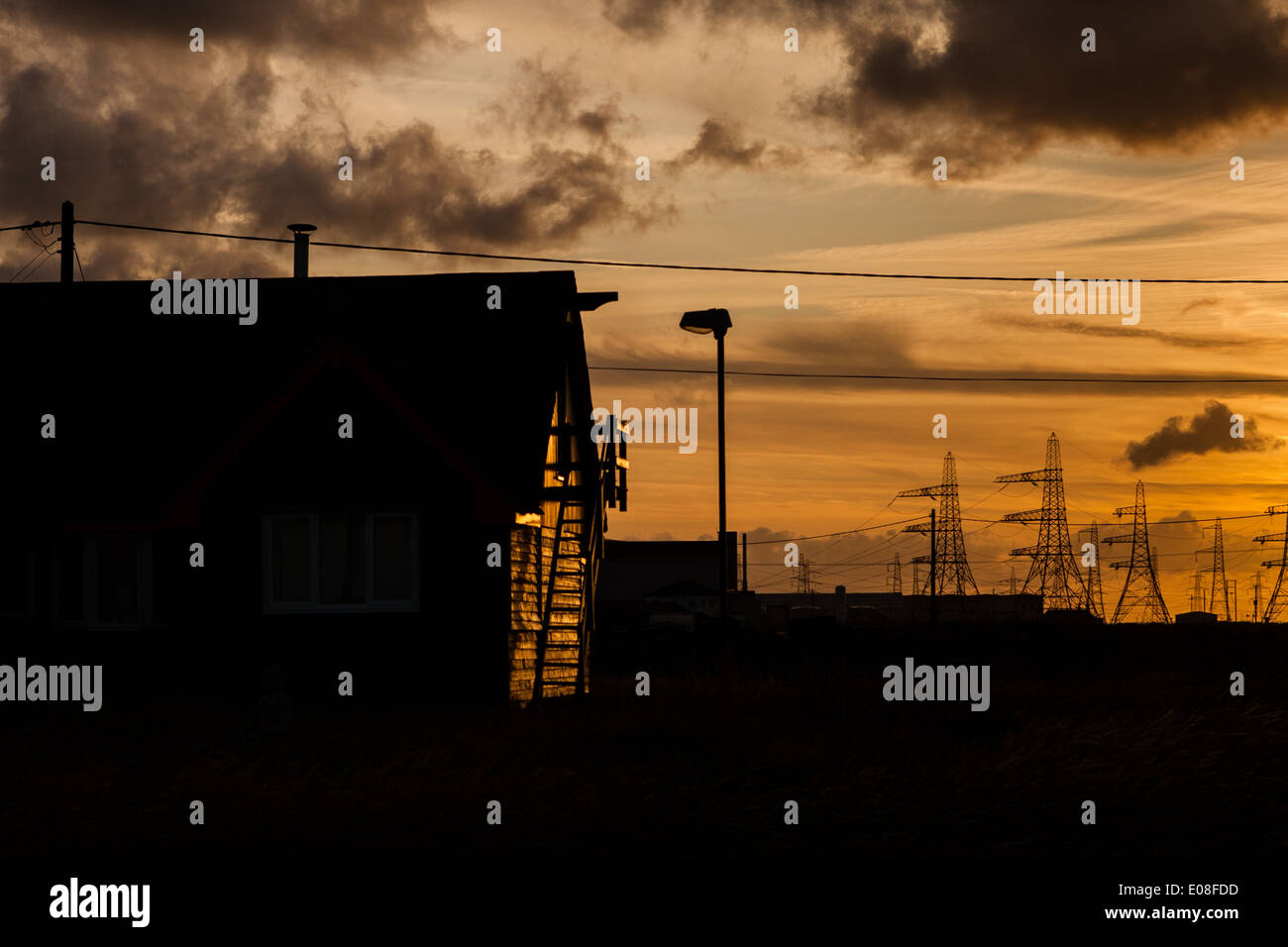 Sunset silhouette of outhouses in Dungeness, Kent, South East England ...