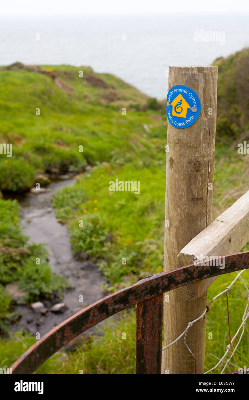 Wales Coastal Path waymarker at a kissing gate - with view of the ...