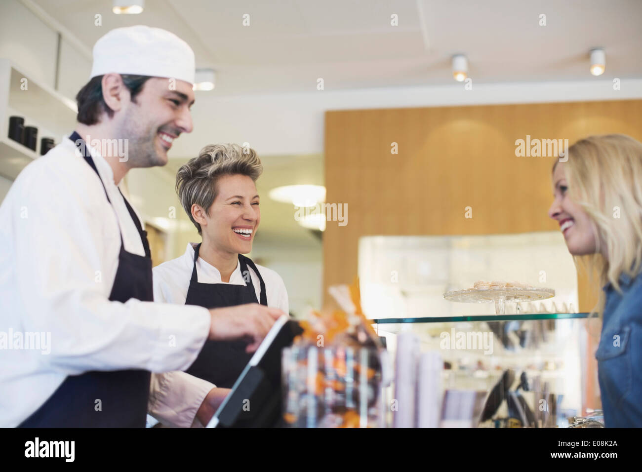 Happy worker attending female customer at cafe counter Stock Photo - Alamy