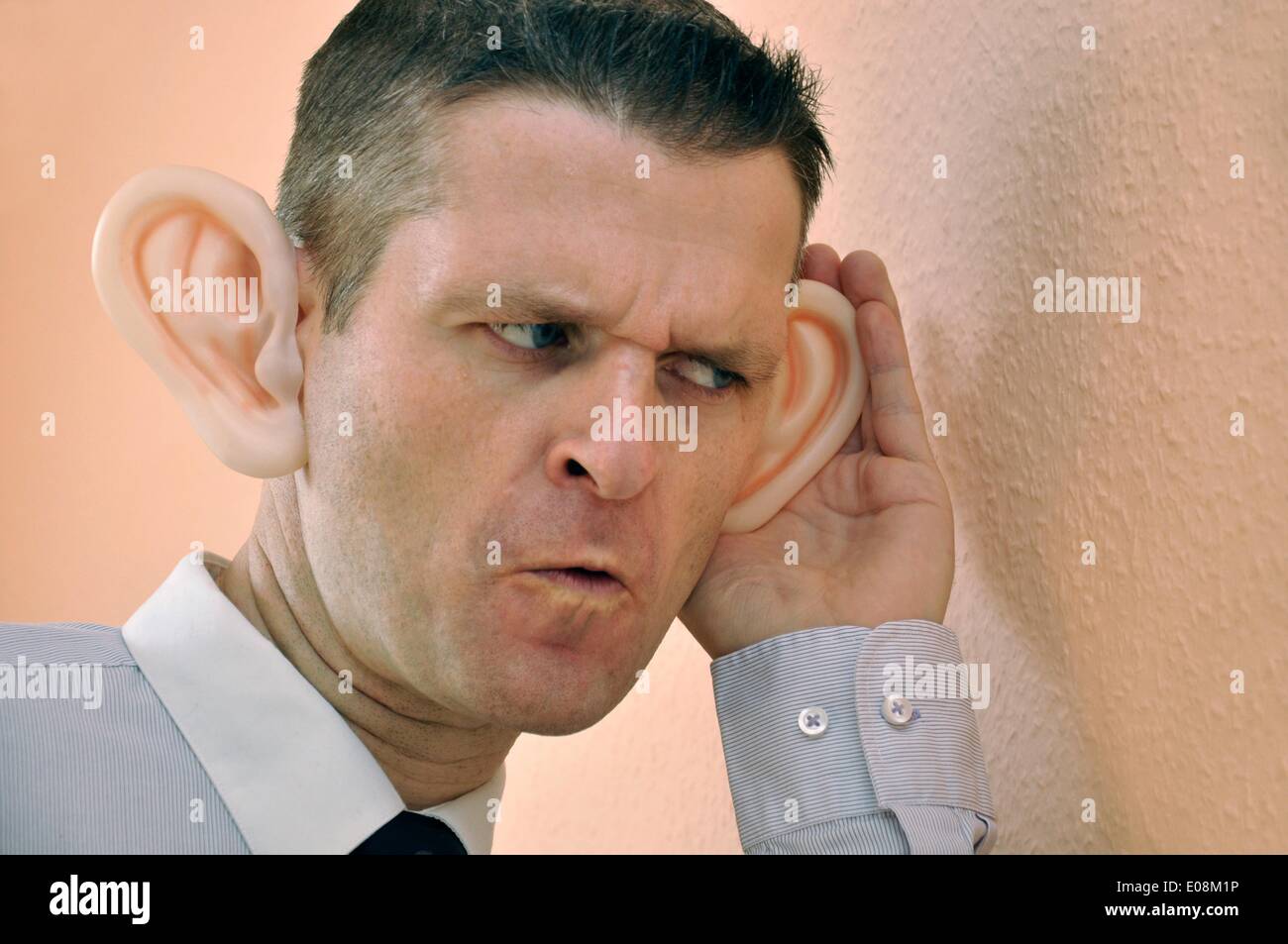 Illustration - A man wearing giant rubber ears spies on a wall in ...