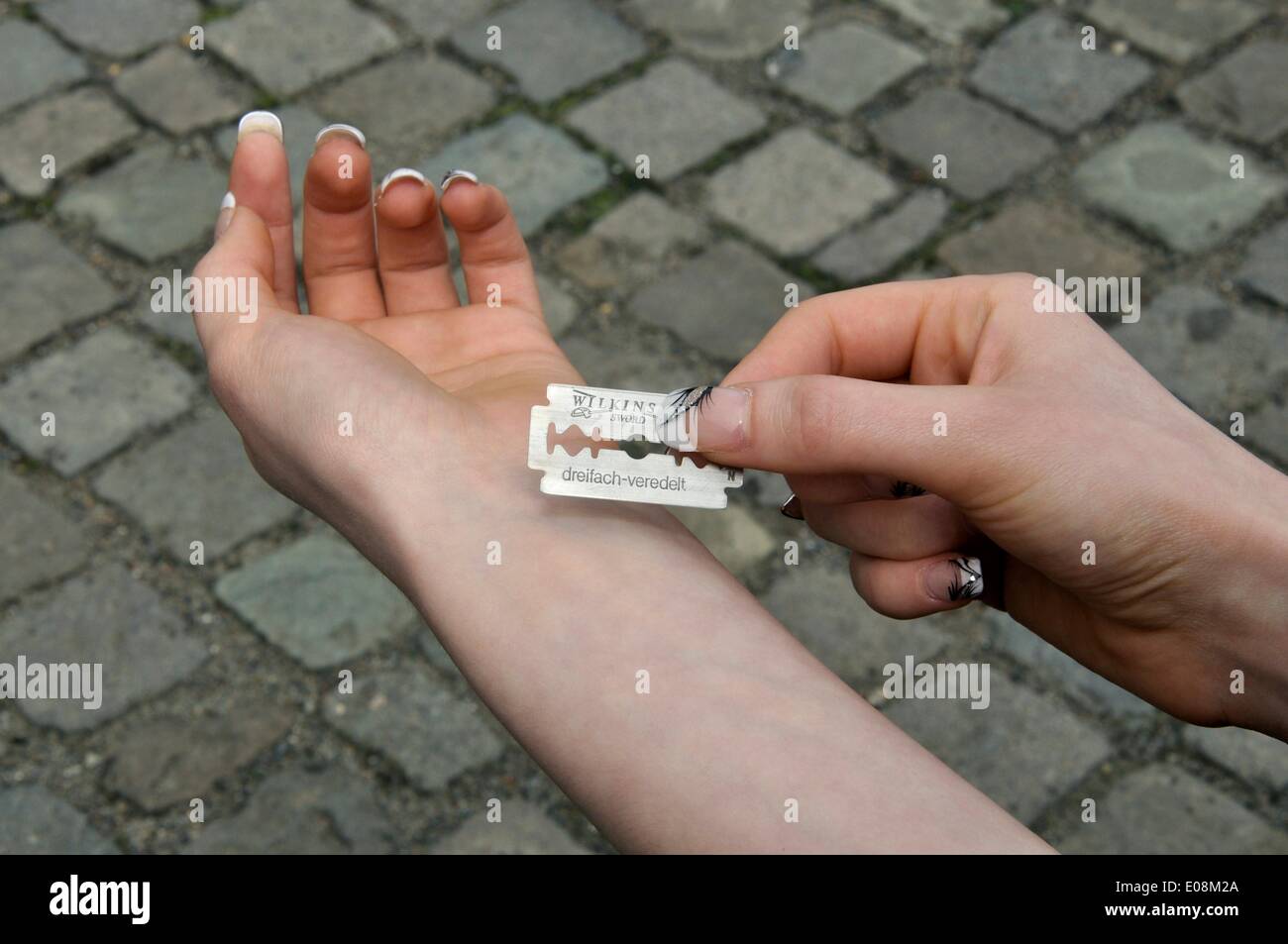 Illustration - A woman holds a razor blade onto the artery on her wrist ...