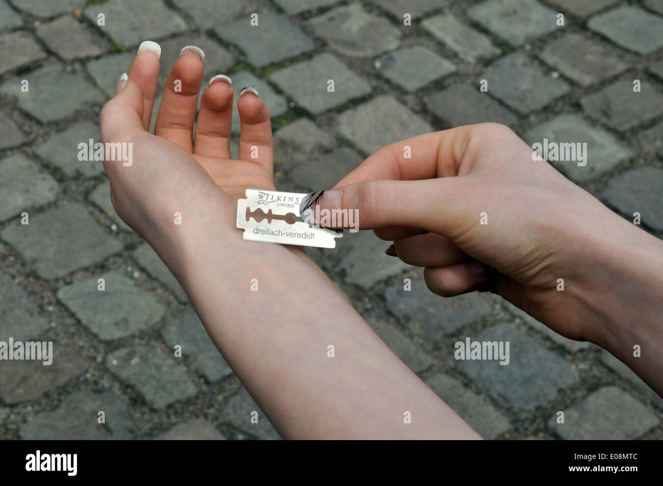 Illustration - A woman holds a razor blade onto the artery on her wrist ...