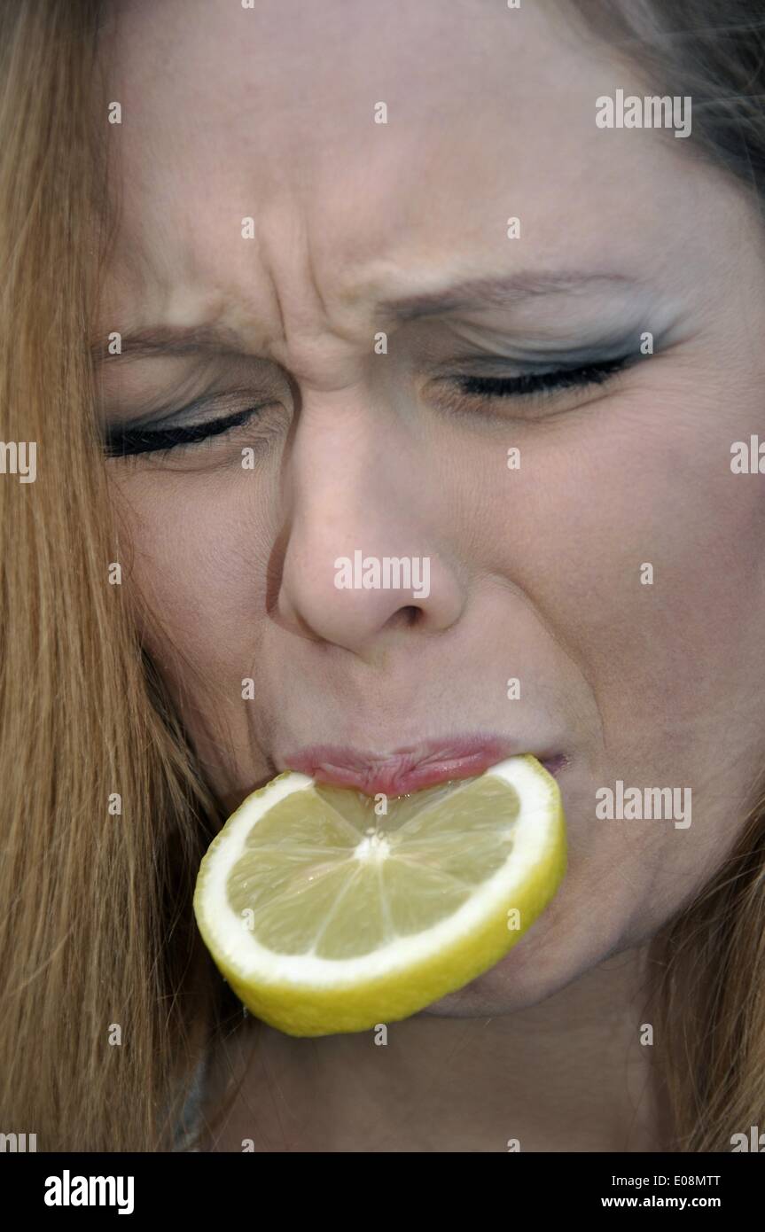 Illustration - A woman grimaces as she bites into a slice of lemon in ...