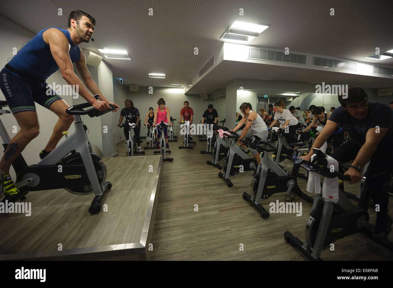 Fitness instructor in front of people riding stationary bicycles during ...