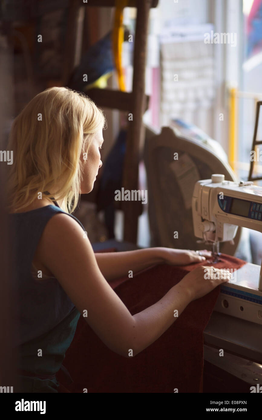Side view of female fashion designer sewing in studio Stock Photo - Alamy