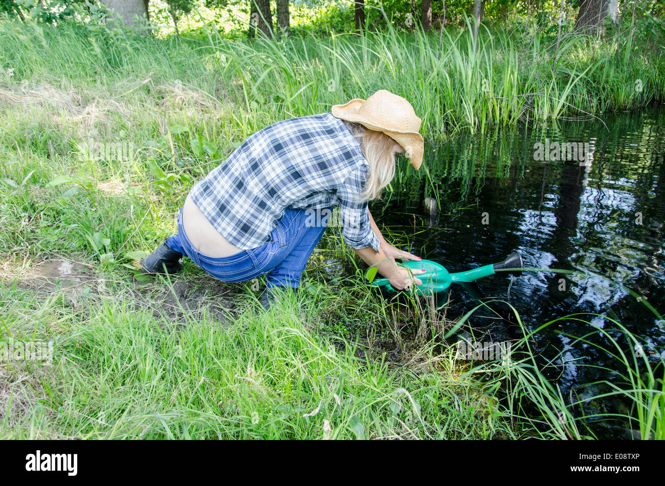Farm gardener girl draw water from pond with watering-can Stock Photo ...