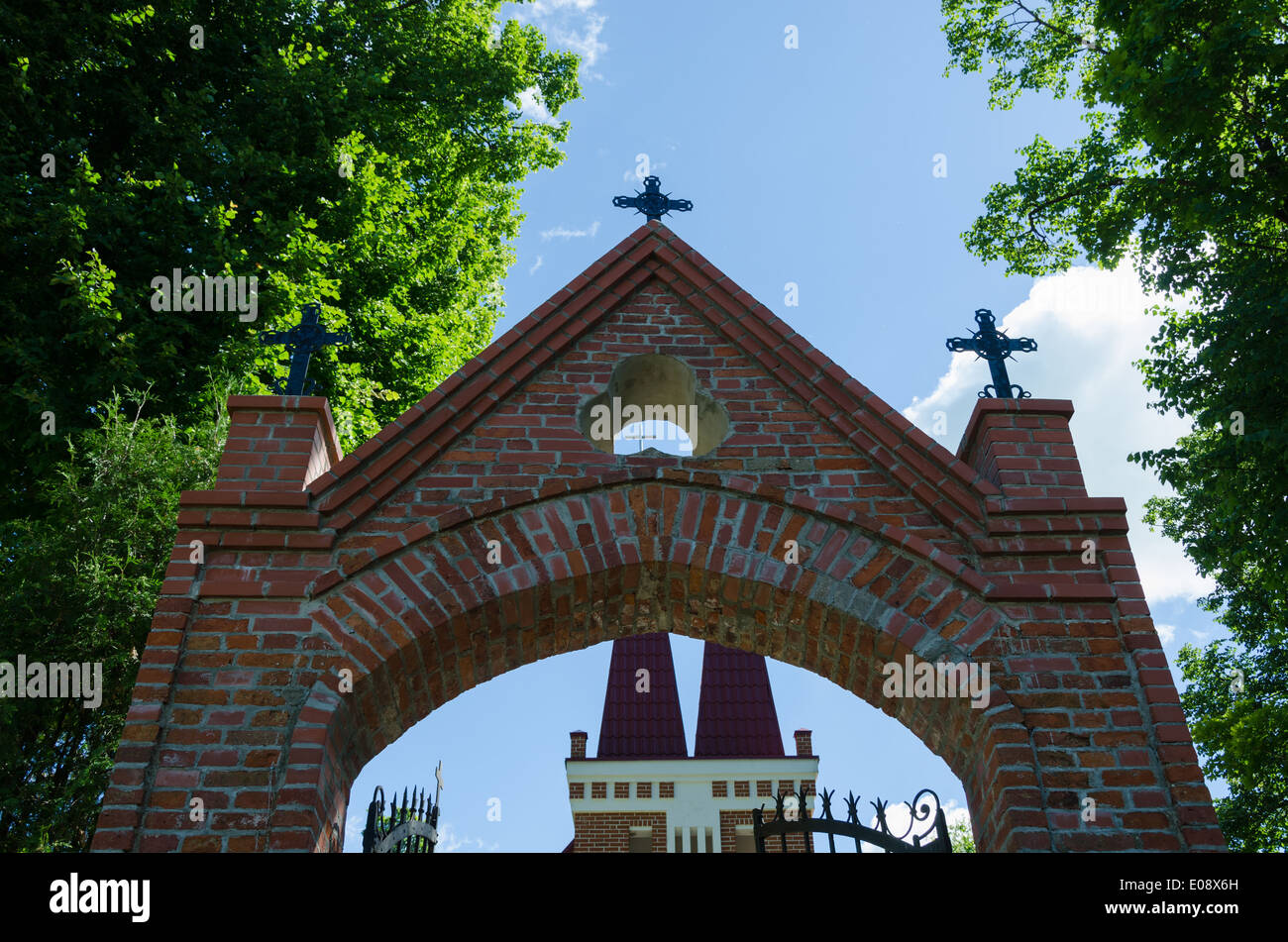 gothic church brick gate with small metallic crosses on blue sky ...