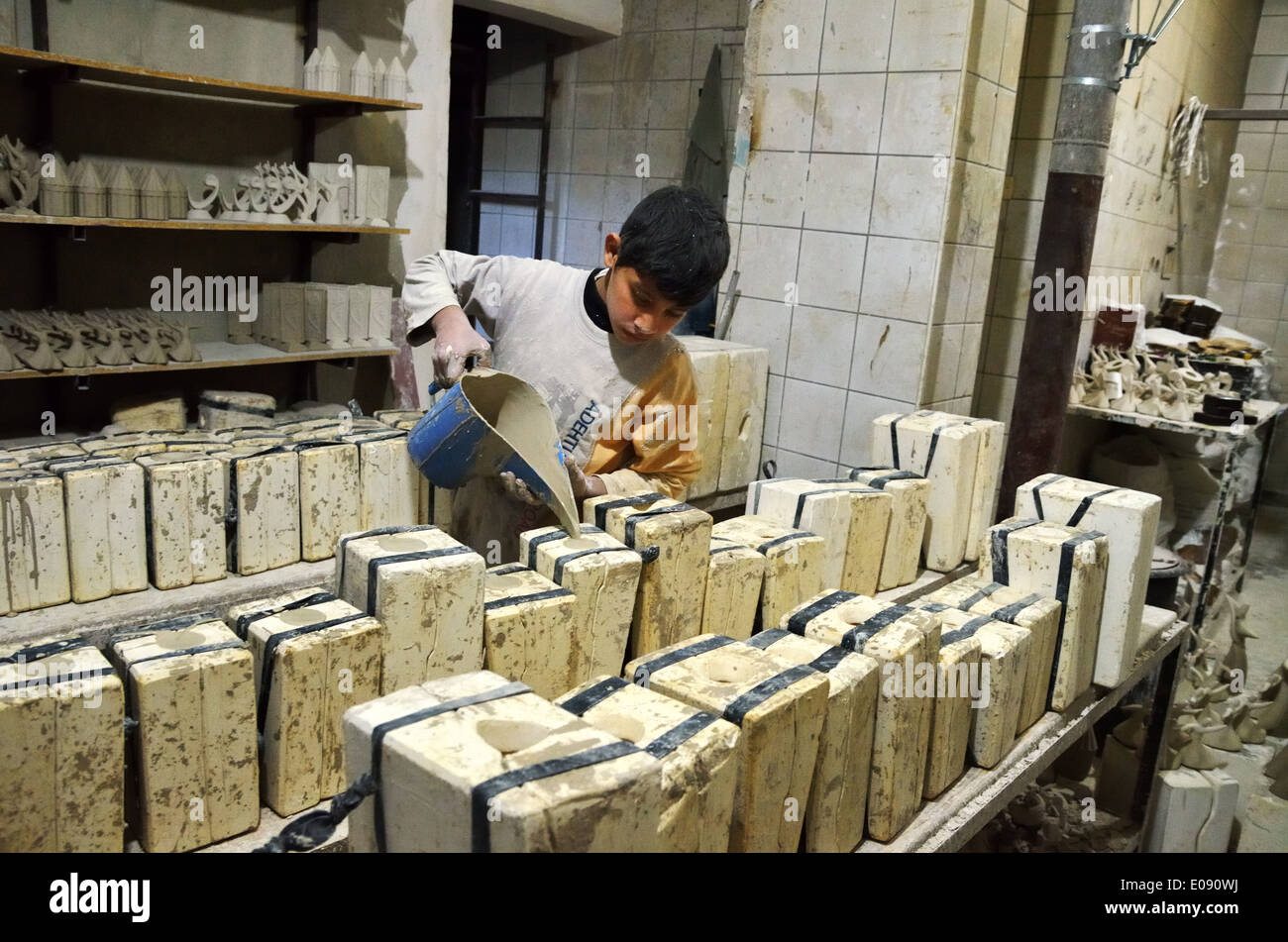 Little boy helps his parents, filling solution in forms of porcelain ...