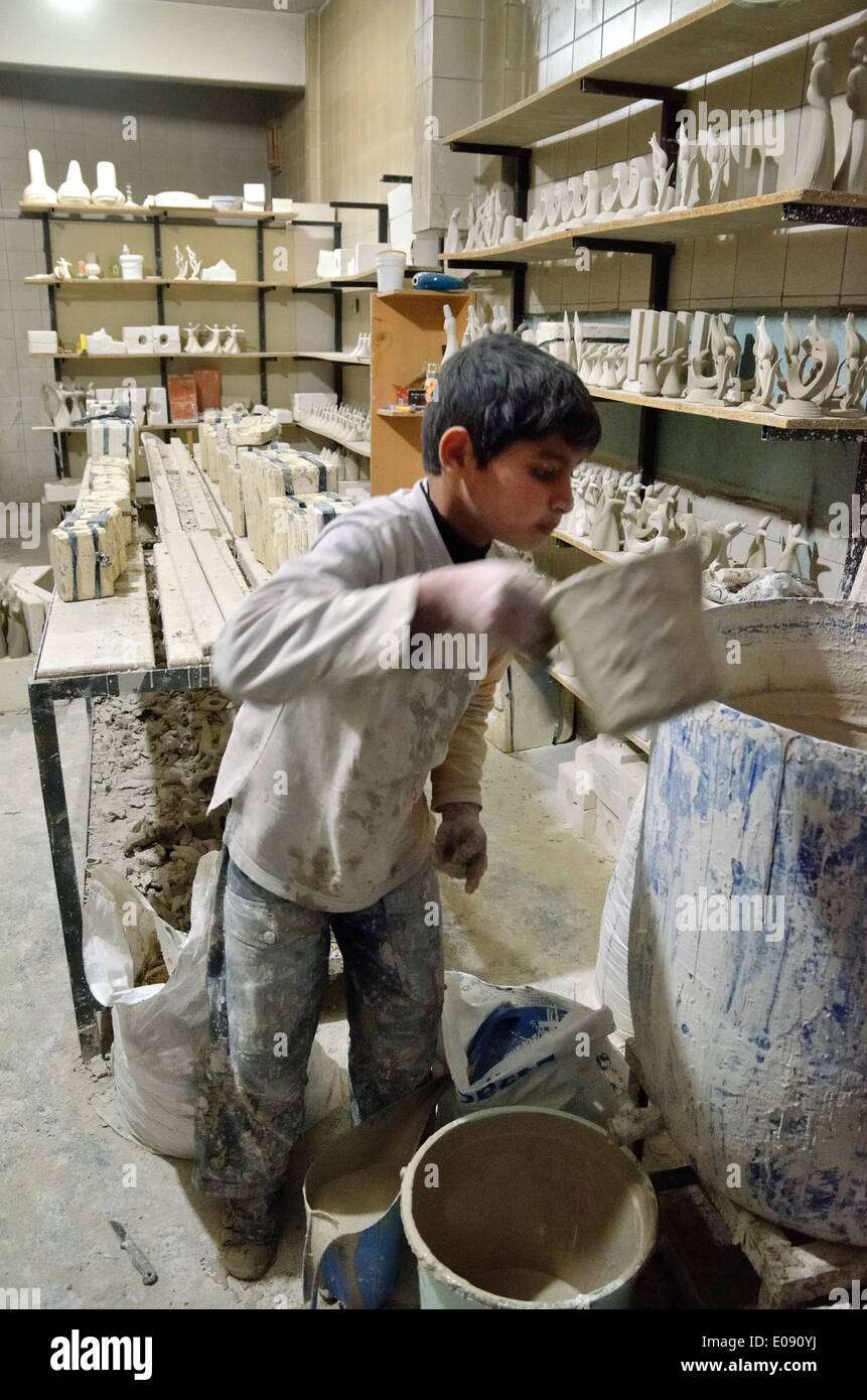 Little boy helps his parents, filling solution in forms of porcelain ...