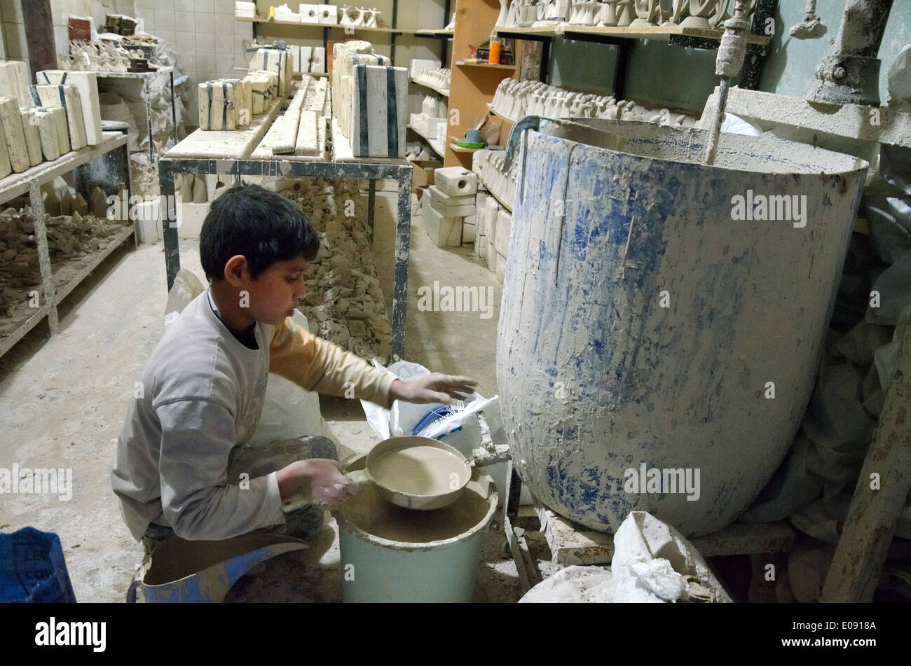 Little boy helps his parents, filling solution in forms of porcelain ...