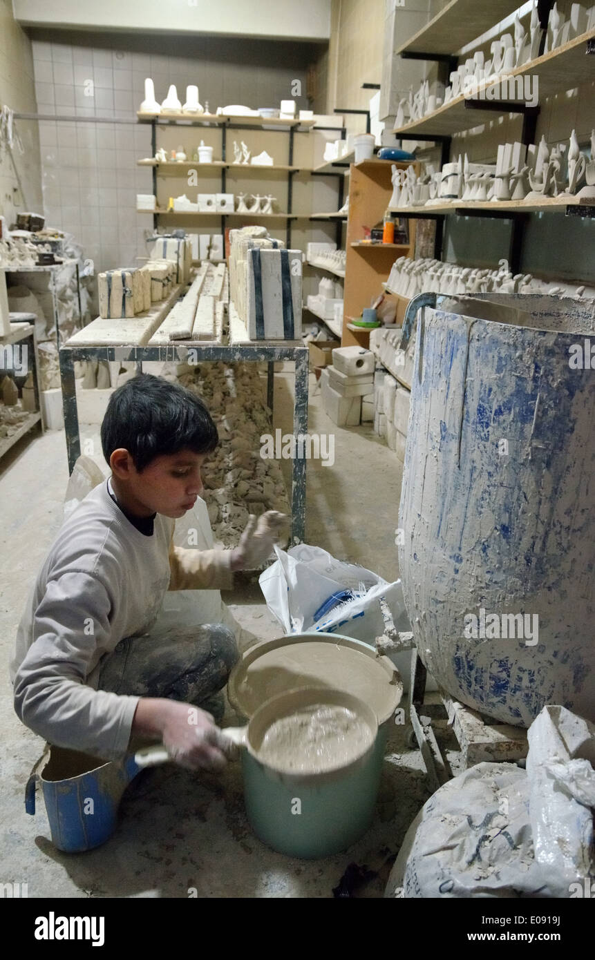 Little boy helps his parents, filling solution in forms of porcelain ...
