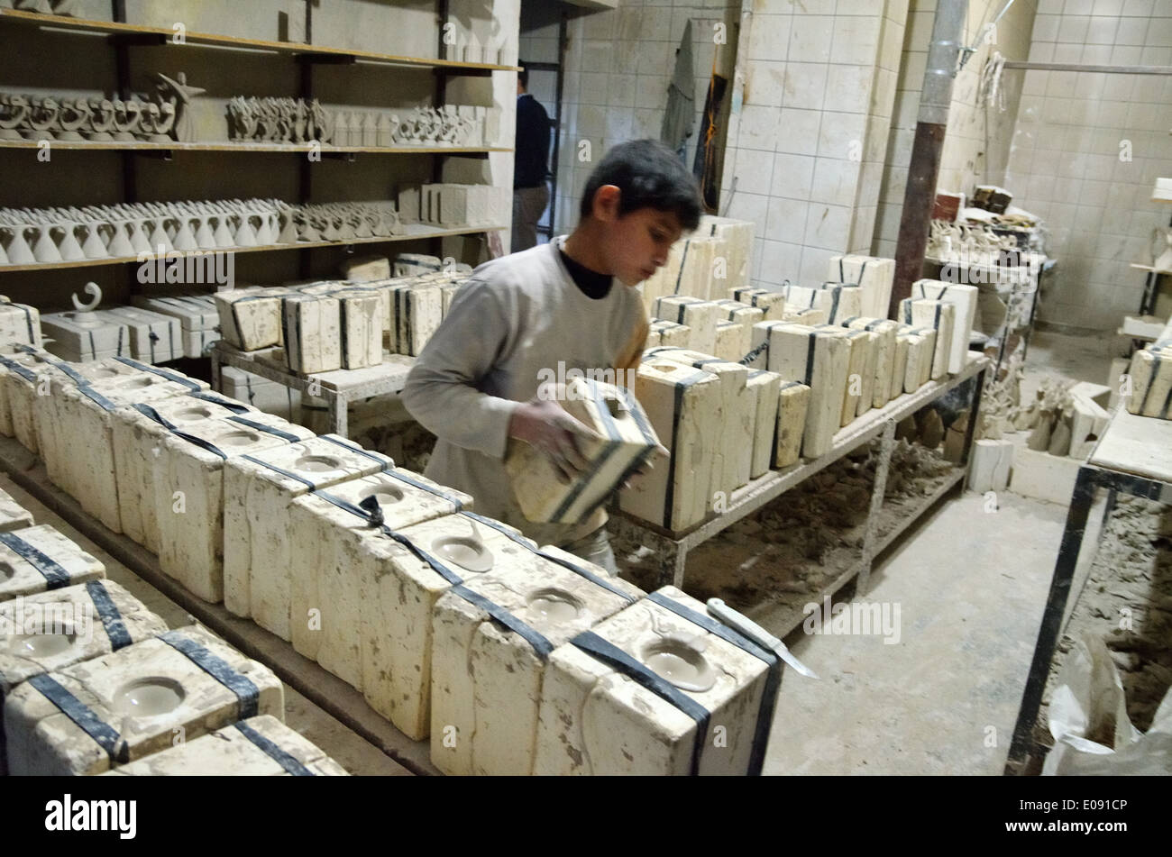 Little boy helps his parents, filling solution in forms of porcelain ...
