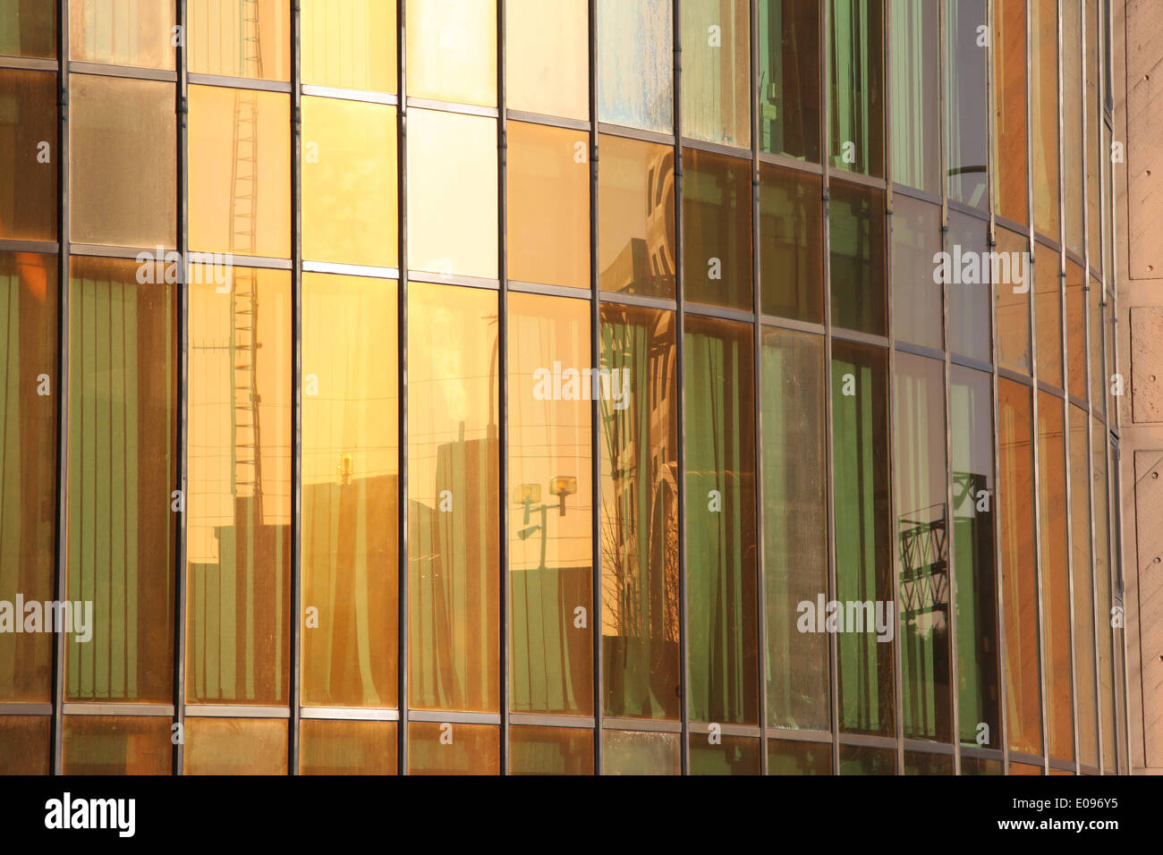 reflection of ladder, street lights,buildings in green and gold glass ...