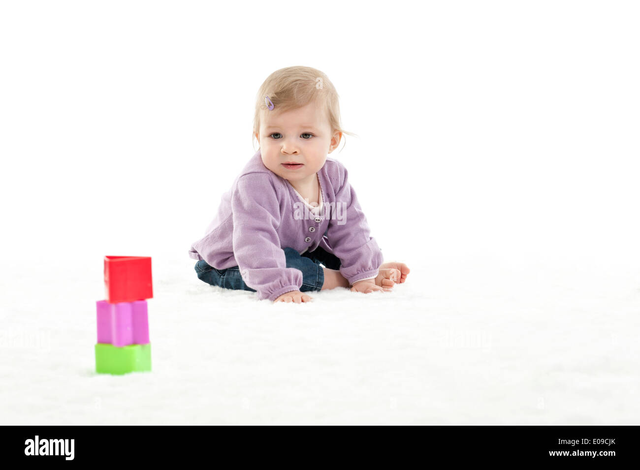 baby seated on a carpet with colored cubes, isolated on white ...