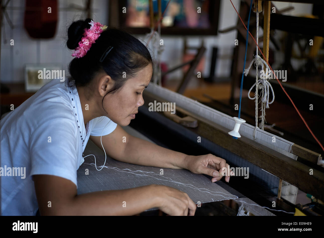 Thai woman working at a traditional wooden weaving loom producing woven ...