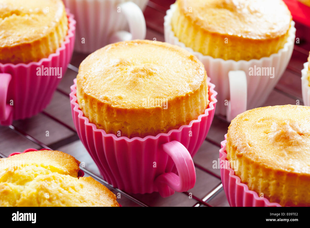 Baking dishes formed like cups with baked cupcakes on cooling grid ...