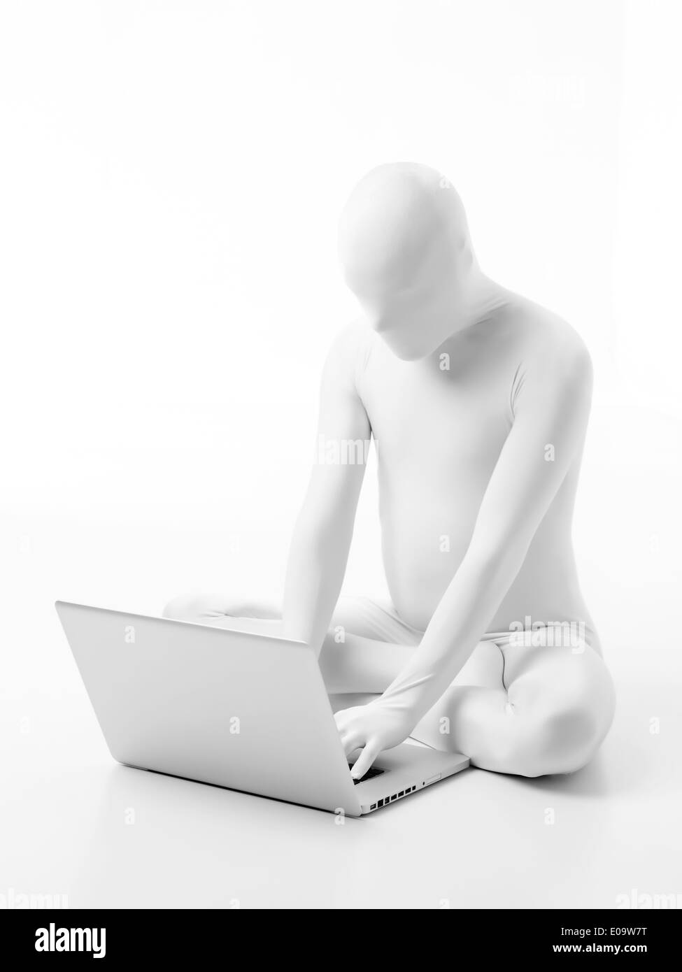 faceless man dressed in white sitting on the floor with laptop typing ...