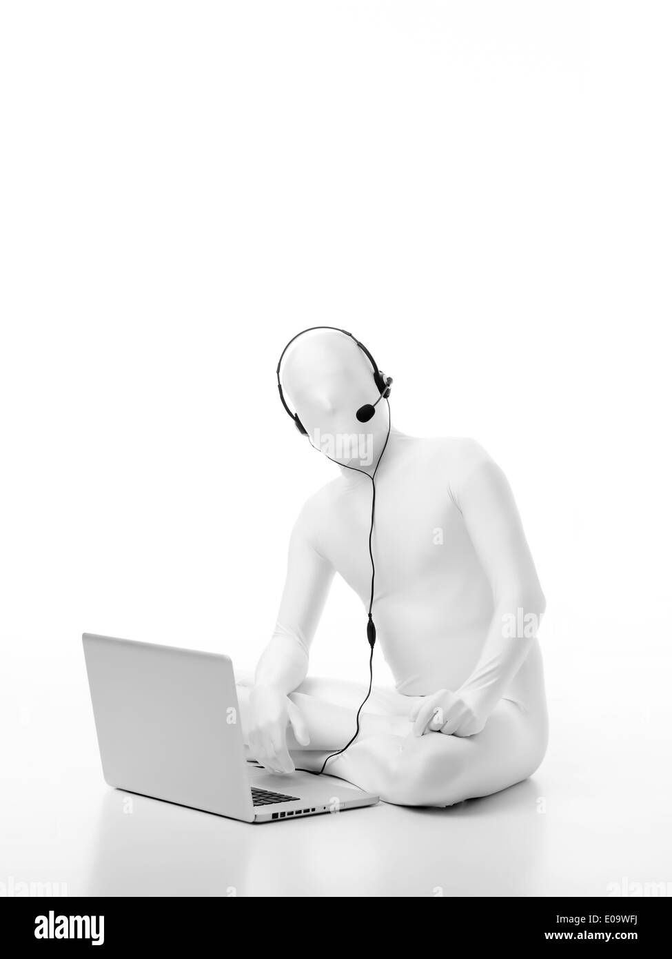 faceless man dressed in white sitting on the floor with a laptop and ...