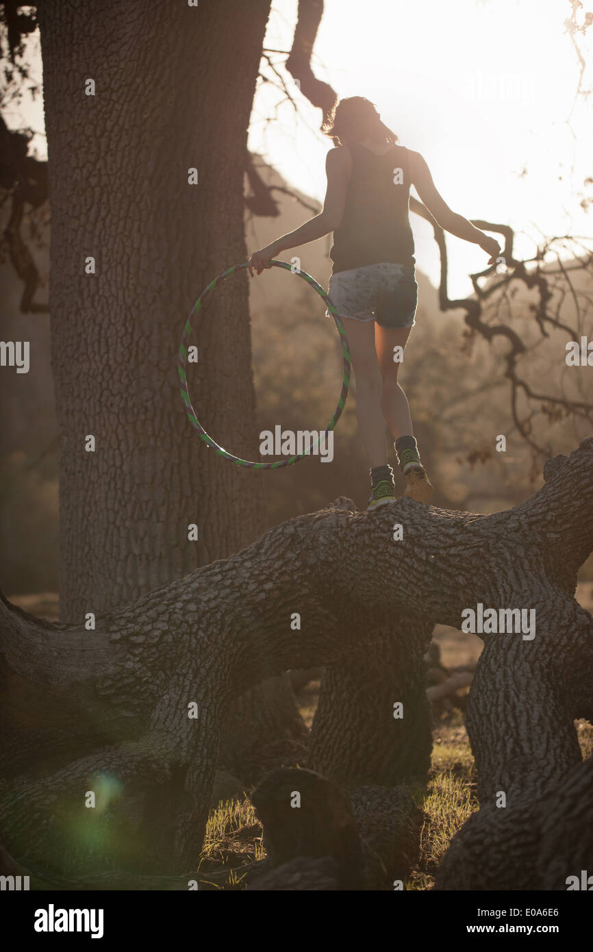 Young woman balancing on fallen tree with hoola hoop, Malibu Creek ...