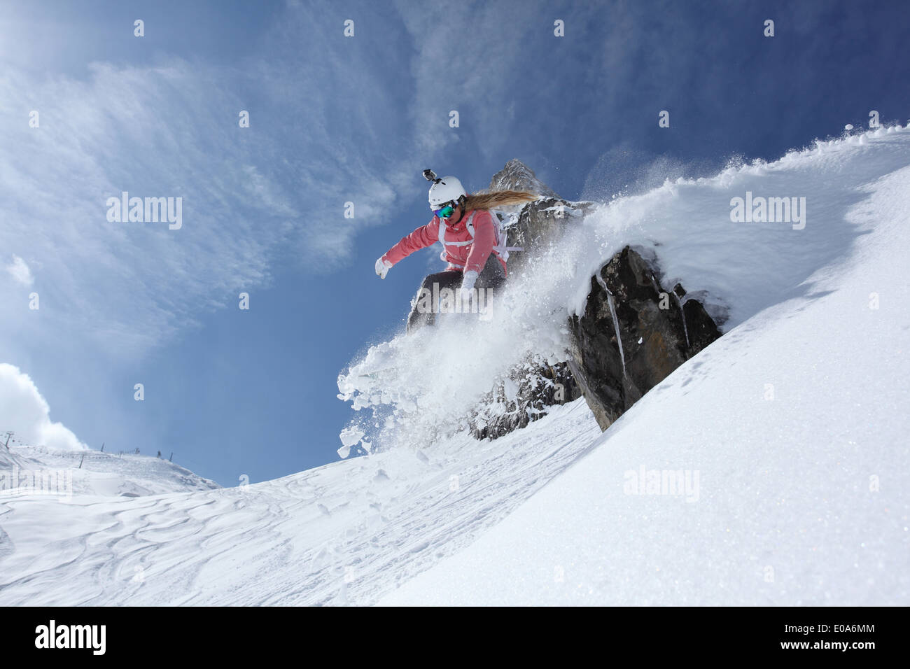 Young female snowboarder jumping off ledge on mountain, Hintertux ...